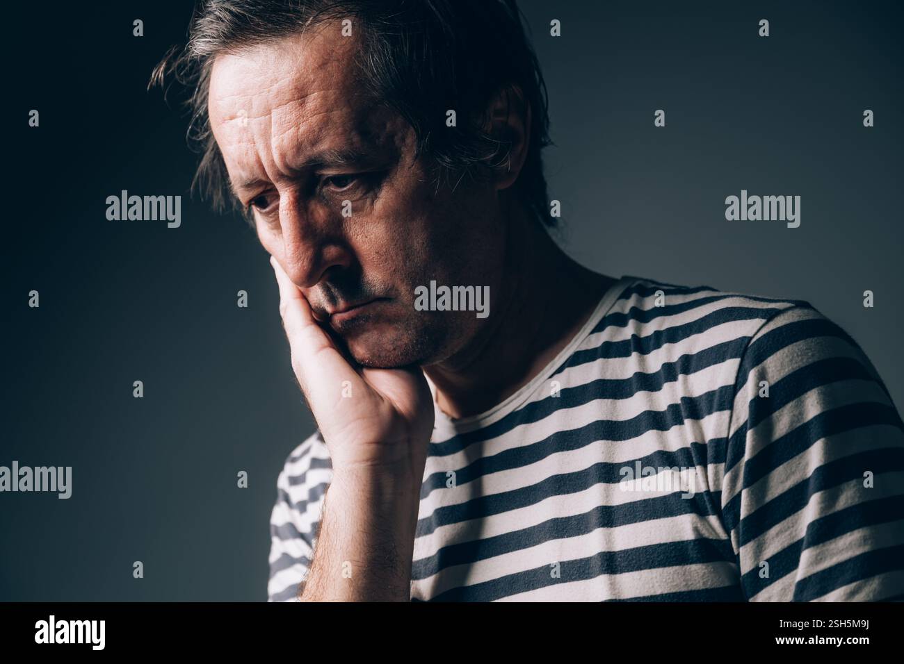 Regretful man with hand on the face, low key portrait of sad distraught ...