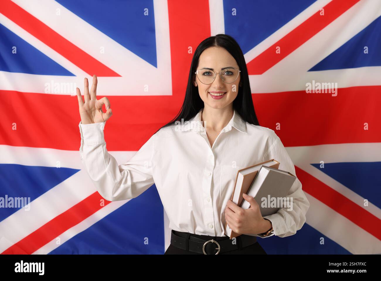 English teacher with books showing ok gesture against UK flag Stock ...