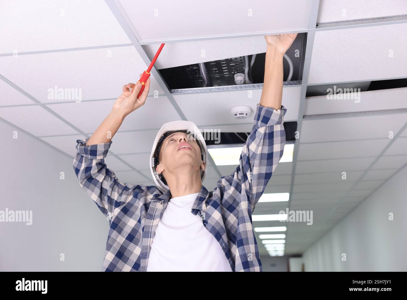 Suspended ceiling installation. Builder working with PVC tile indoors ...