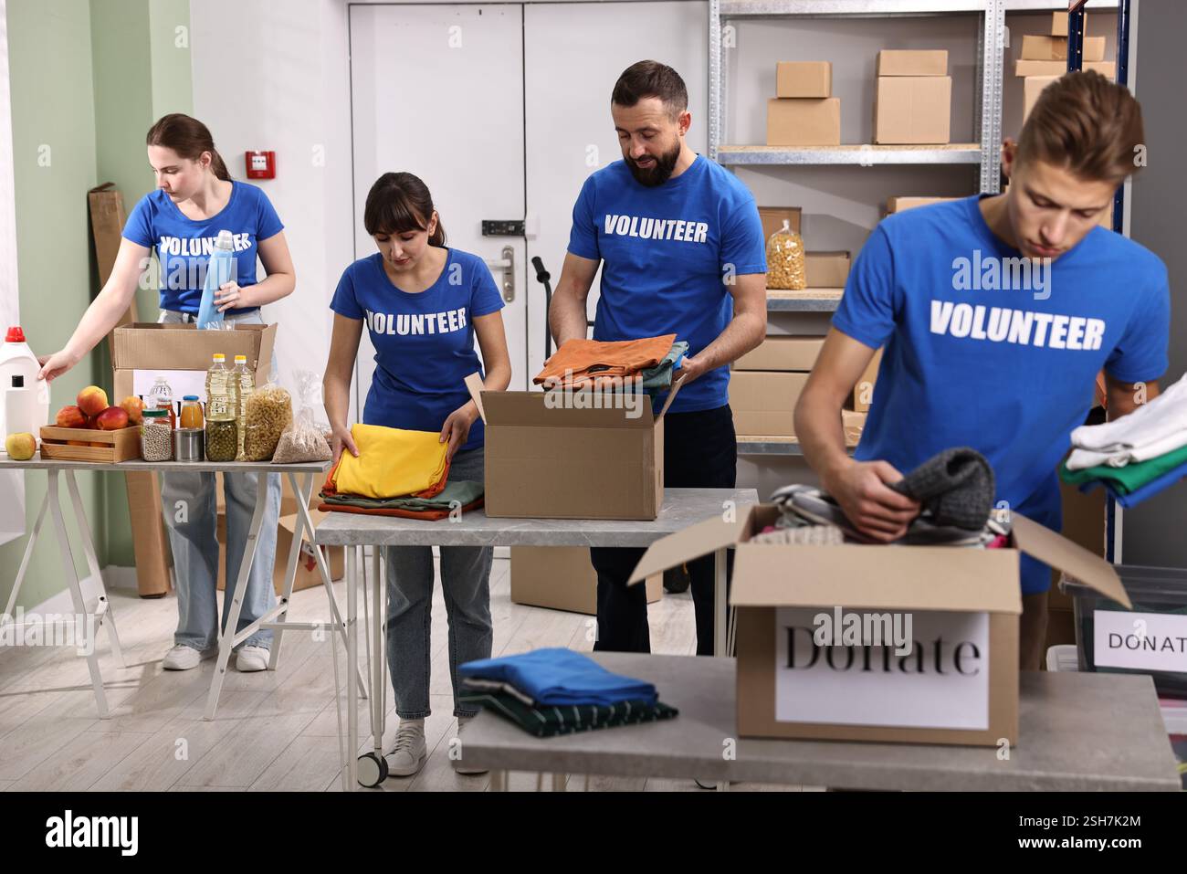 Group of volunteers packing donation goods at tables indoors Stock ...