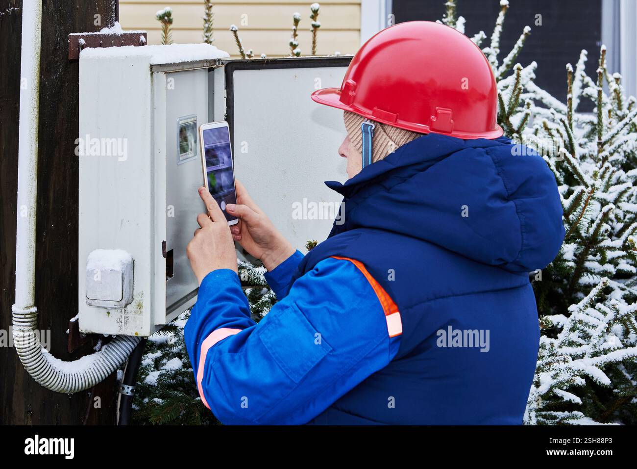Utility service worker ensuring electric meter is functioning properly ...