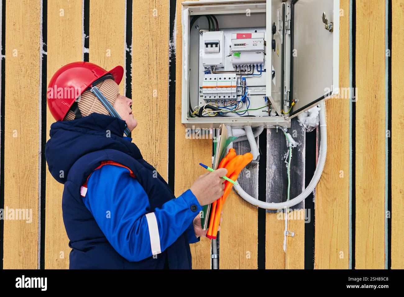 Female meter reading clerk inspects an electrical panel for maintenance ...