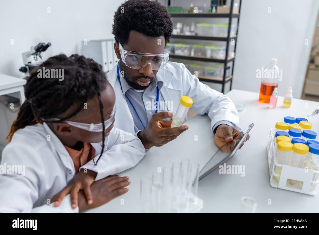 Male teacher of science showing to a school girl how to use vacutainers ...