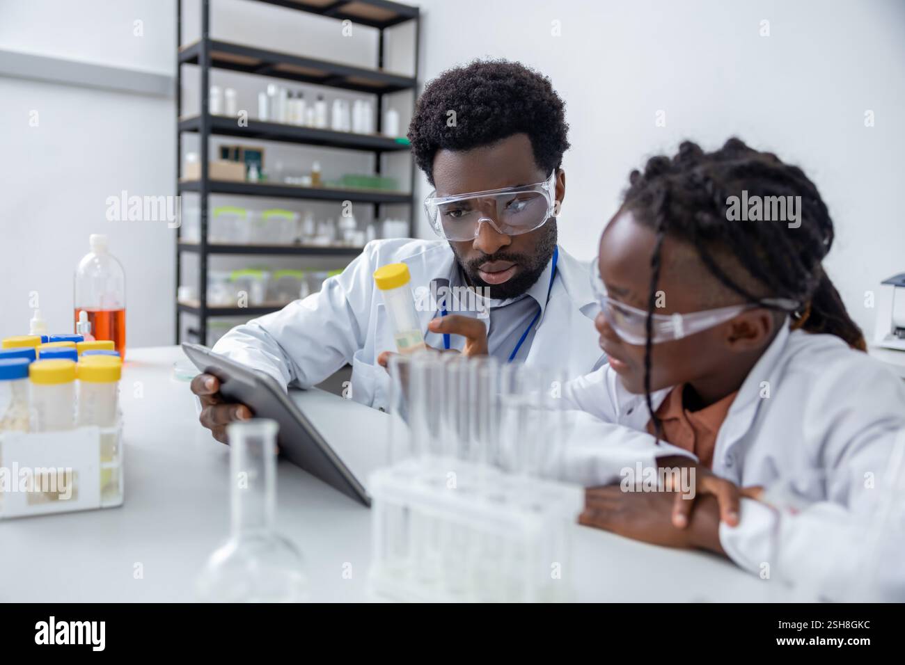 Male teacher of science showing to a school girl how to use vacutainers ...