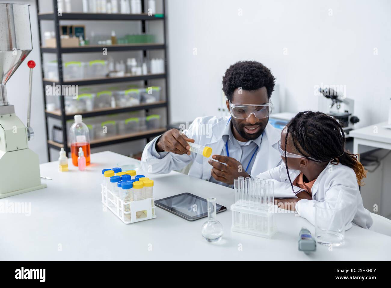 Male teacher of science showing to a school girl how to use vacutainers ...