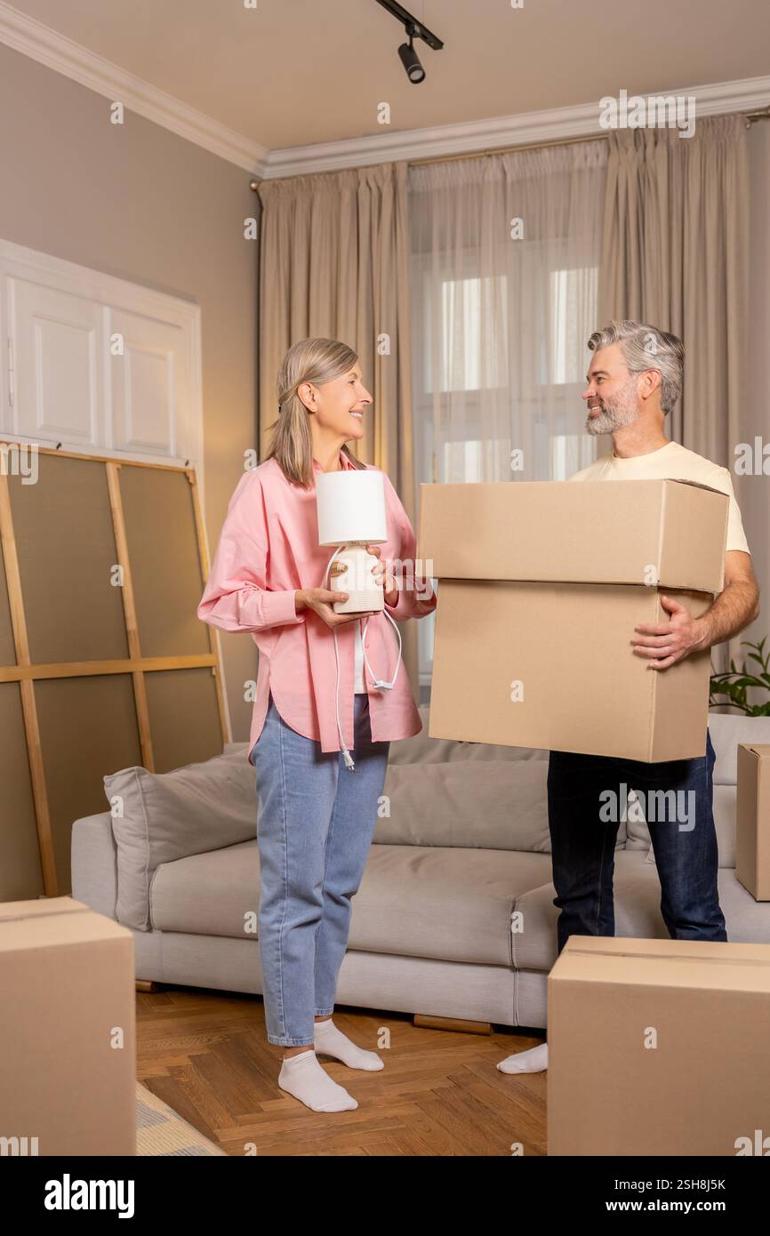 Senior couple moving house packing boxes with belongings together in ...
