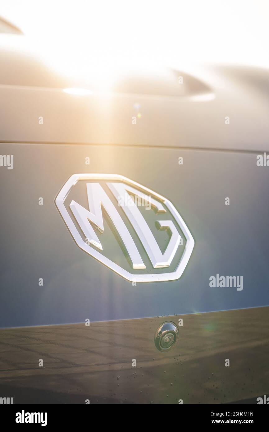 MG logo in the beam of light, focus on the shiny logo, e-car sharing ...