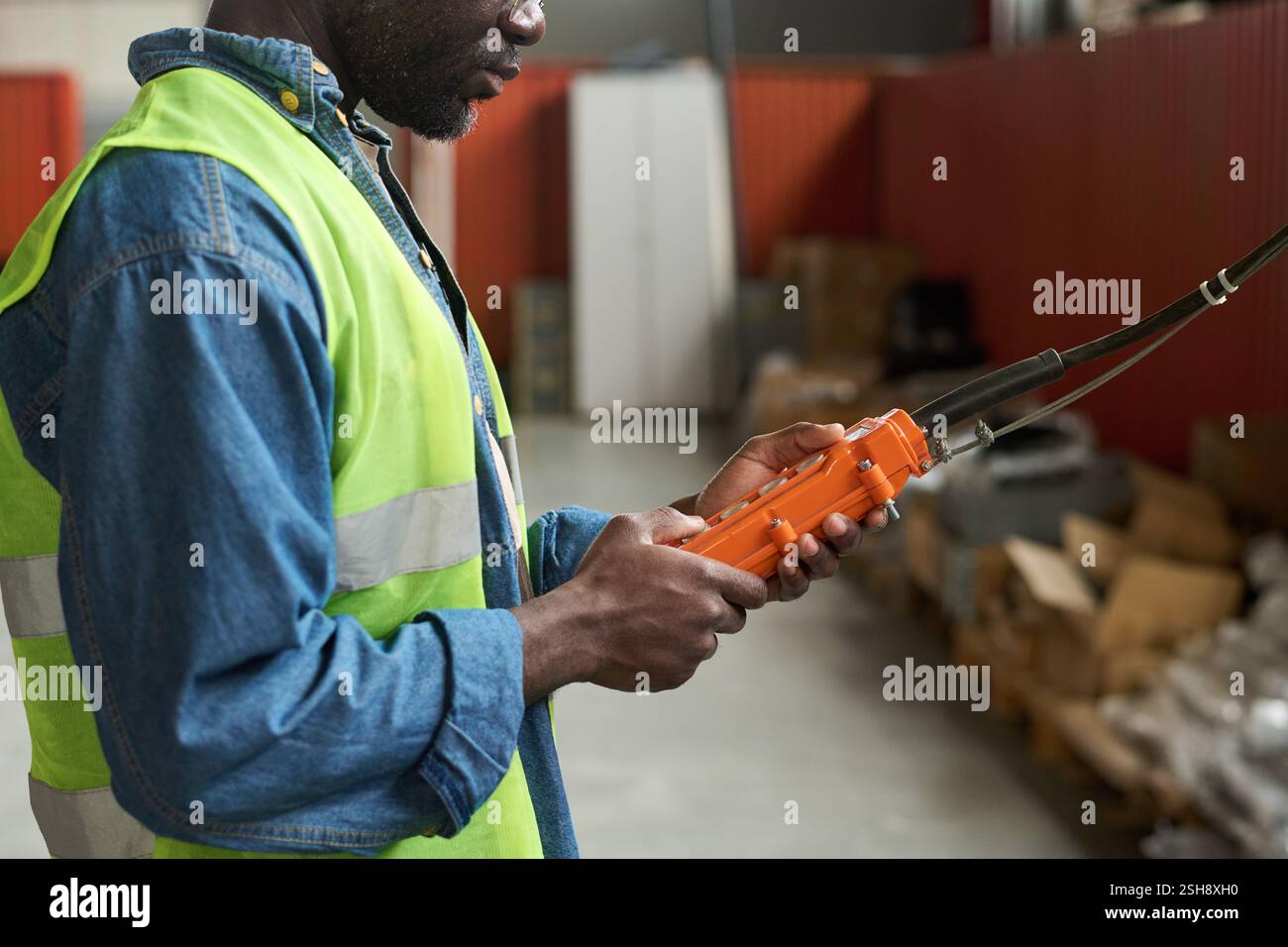 Hands of young male modern factory worker using control pad while ...