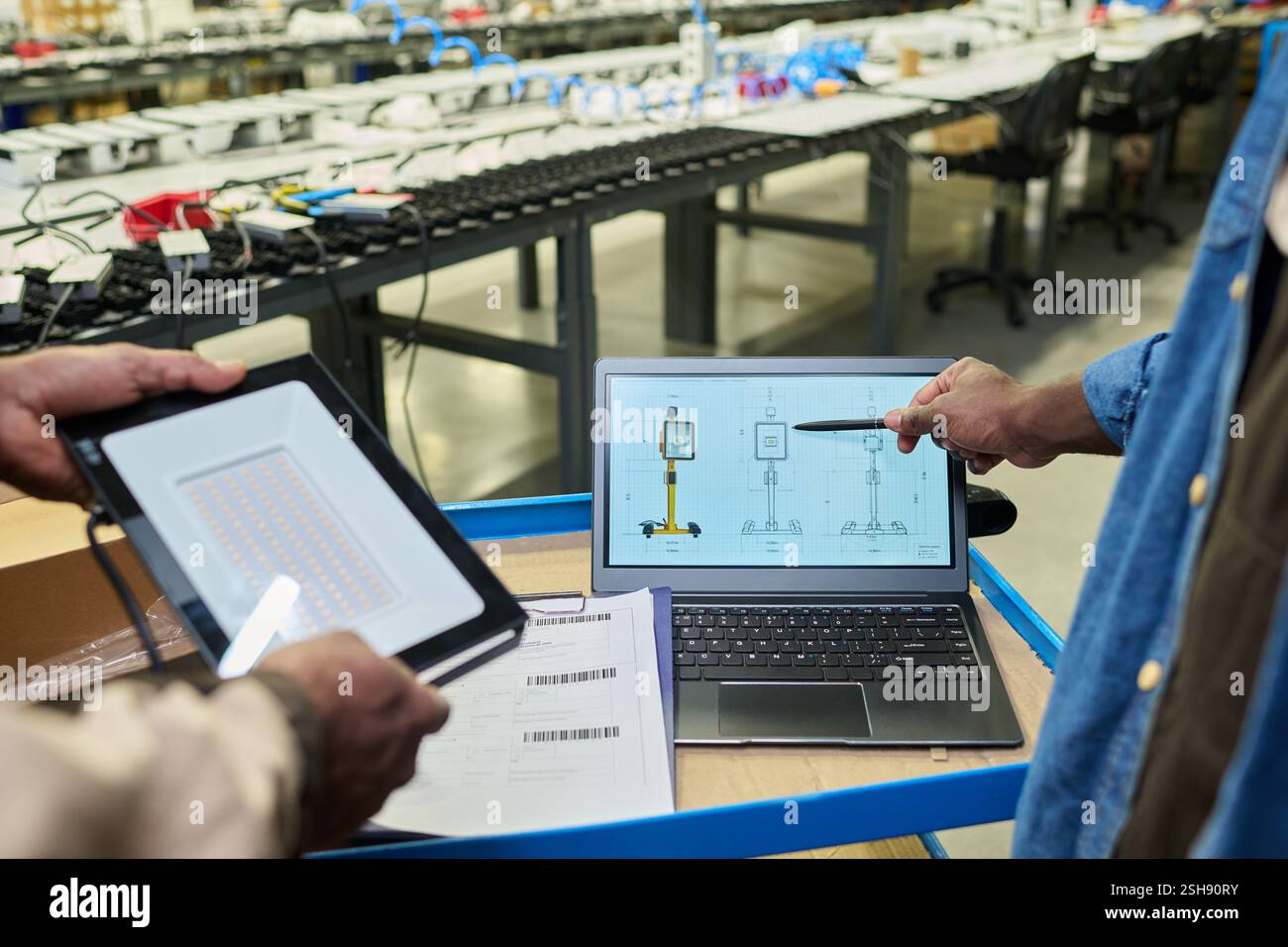 Hand of male worker of factory pointing at laptop screen with schemes ...