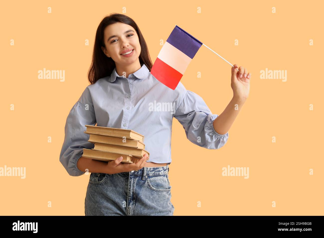 Female French language teacher with books and flag on yellow background ...