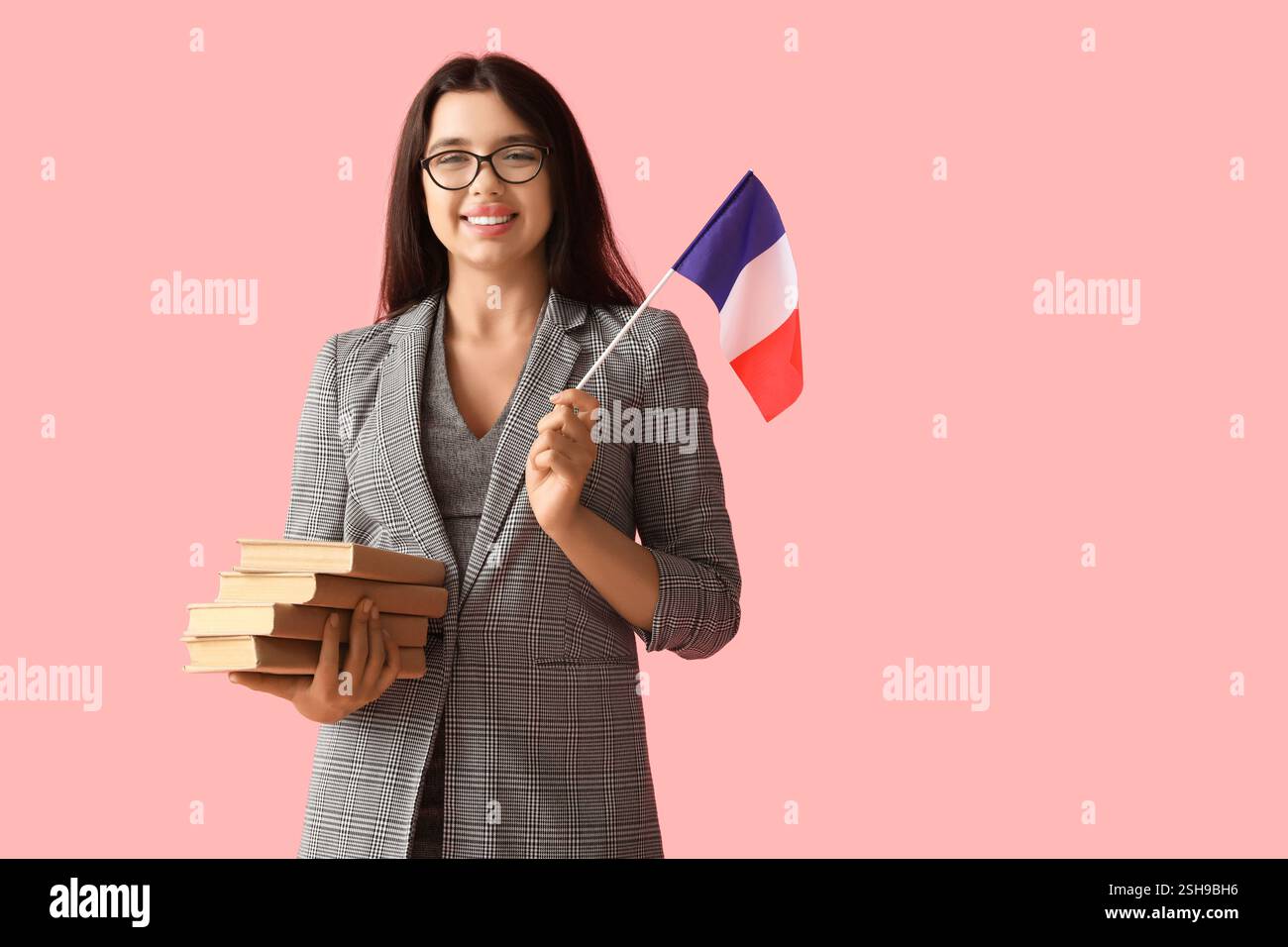 Female French language teacher with books and flag on pink background ...