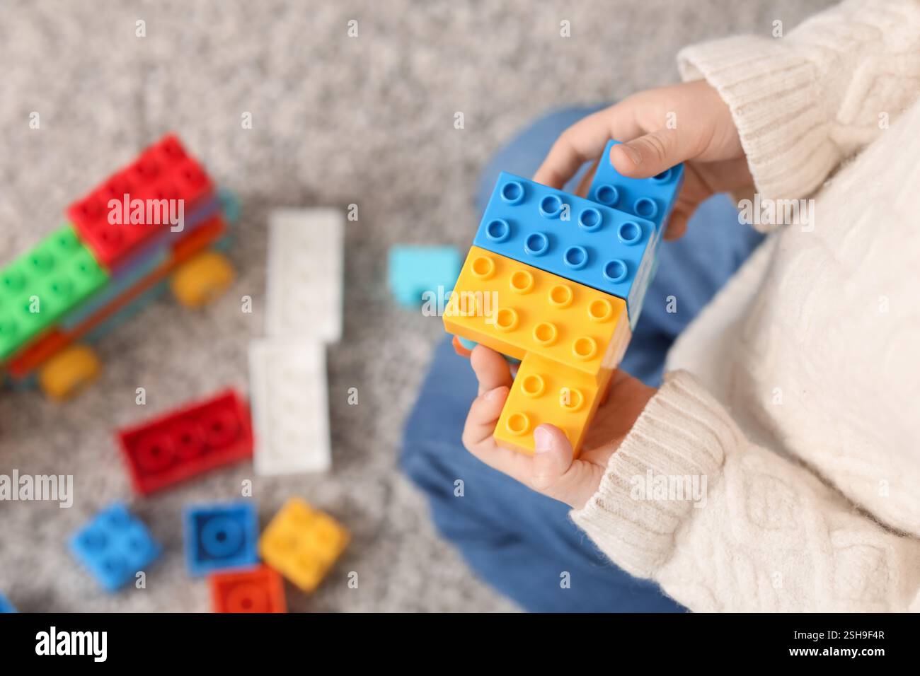 Cute little boy playing with colorful toy bricks on floor at home, top ...