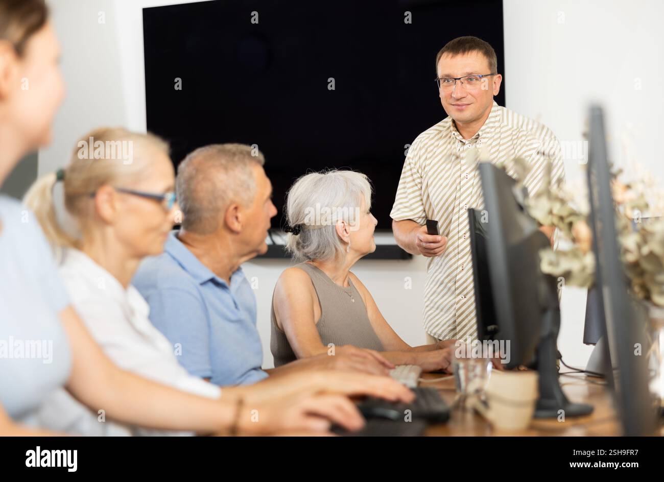 Male teacher teaching elderly people how to use computer Stock Photo ...