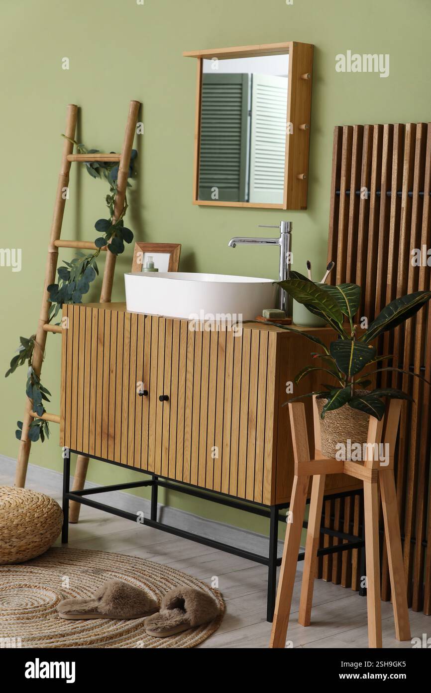 Chest of drawers, stepladder and folding screen near green wall in ...