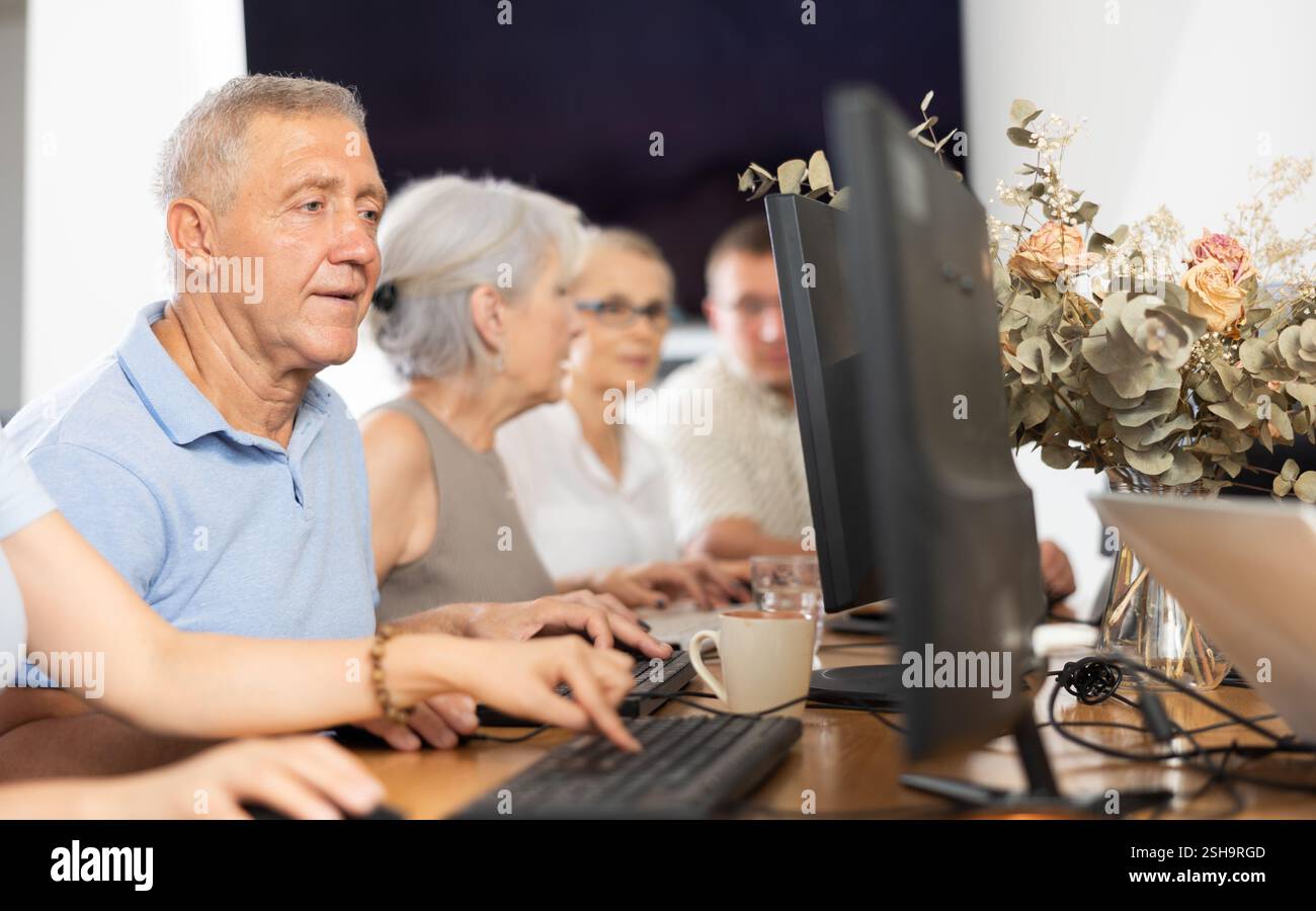 Elderly man taking computer lessons with group of elderly people in ...