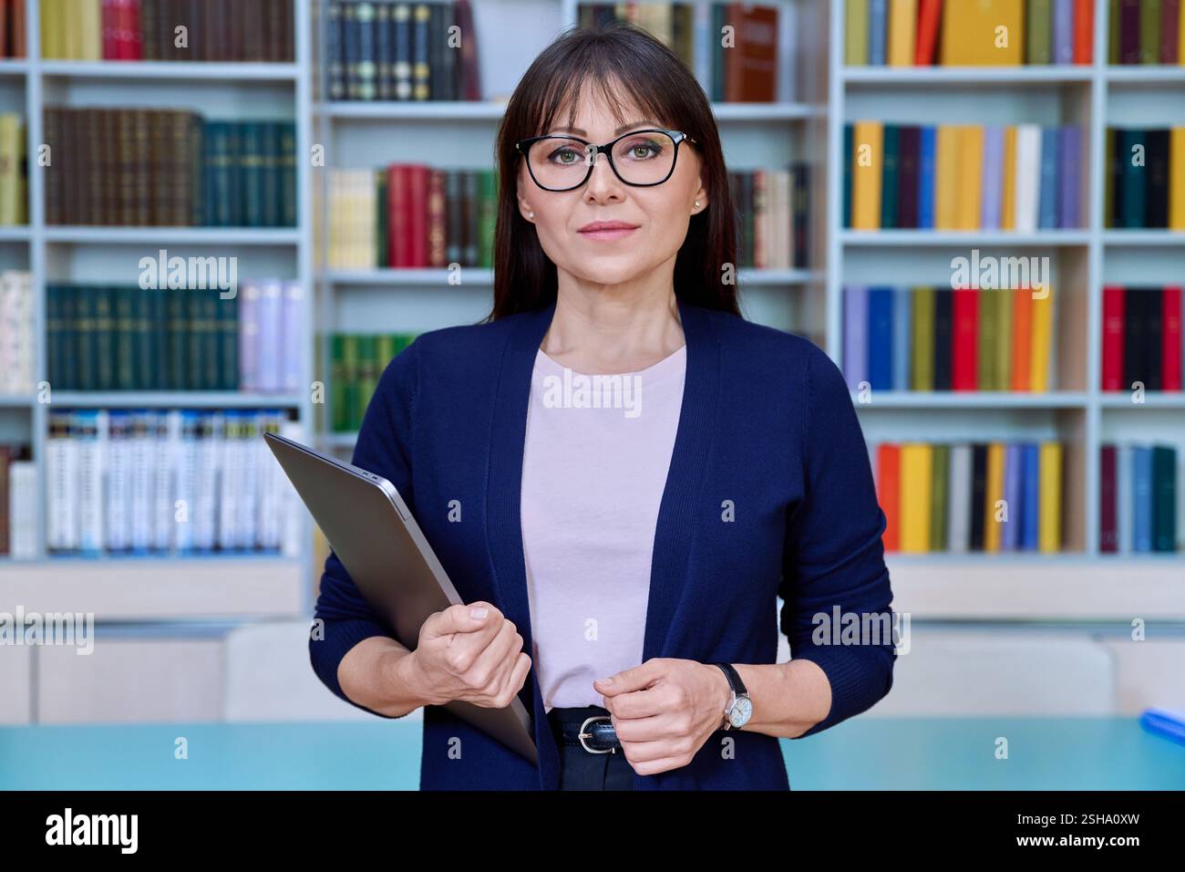 Portrait of middle aged serious woman teacher professor with laptop ...
