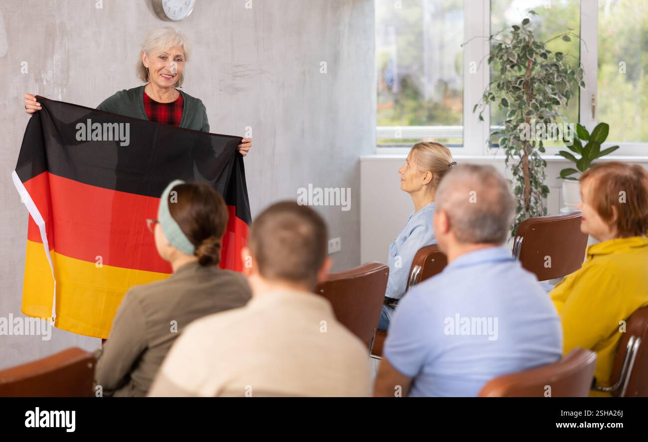 Mature female professor showing german flag to elderly students Stock ...