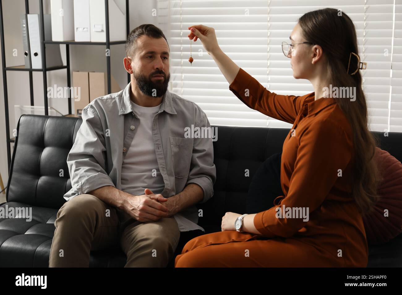 Psychologist using pendulum while working with patient during hypnosis ...