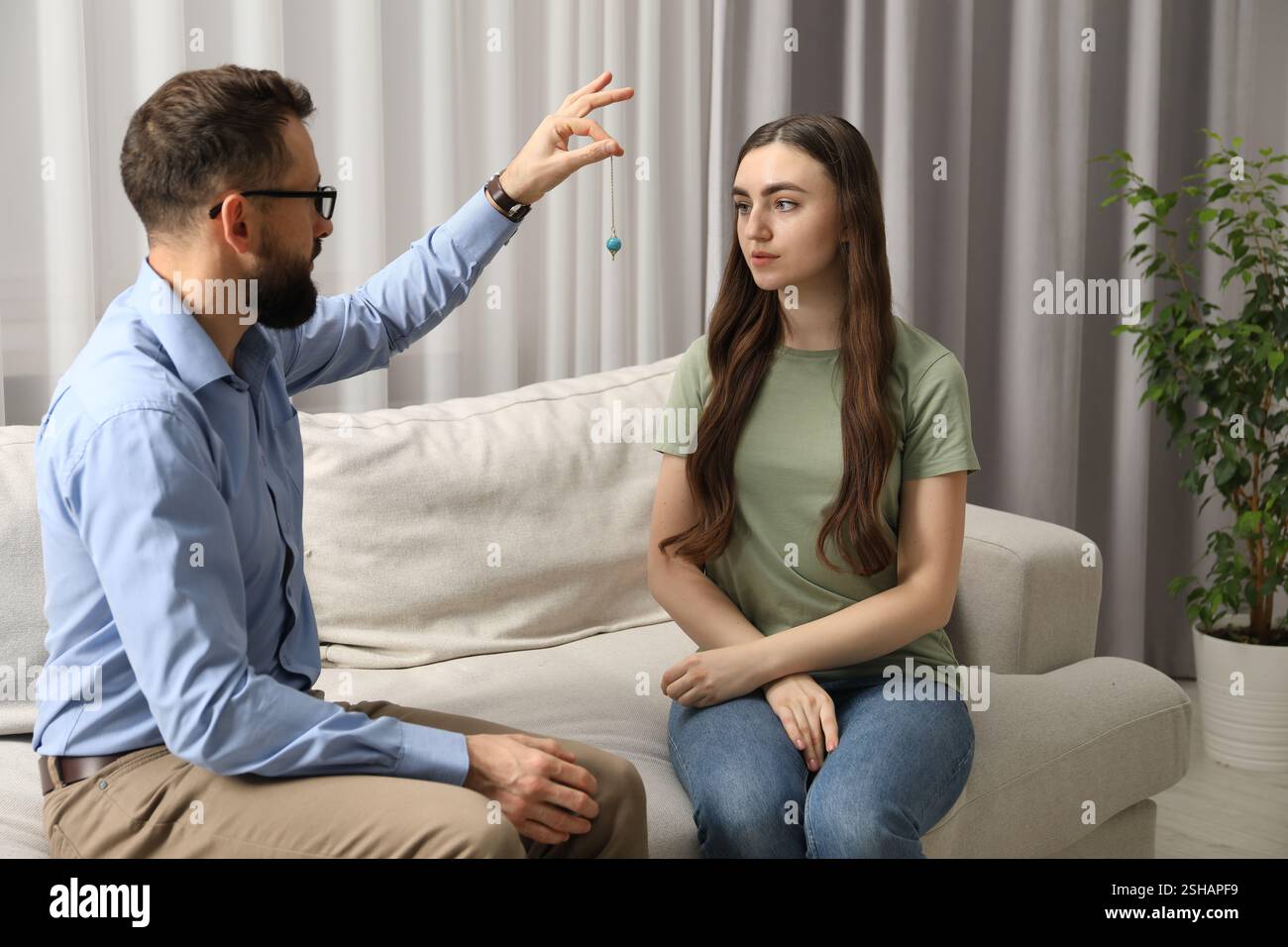 Psychologist using pendulum while working with patient during hypnosis ...