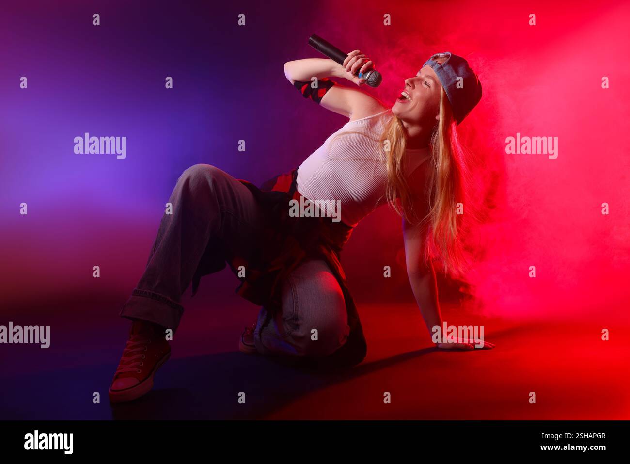 Talented singer performing on dark background with color lights and ...
