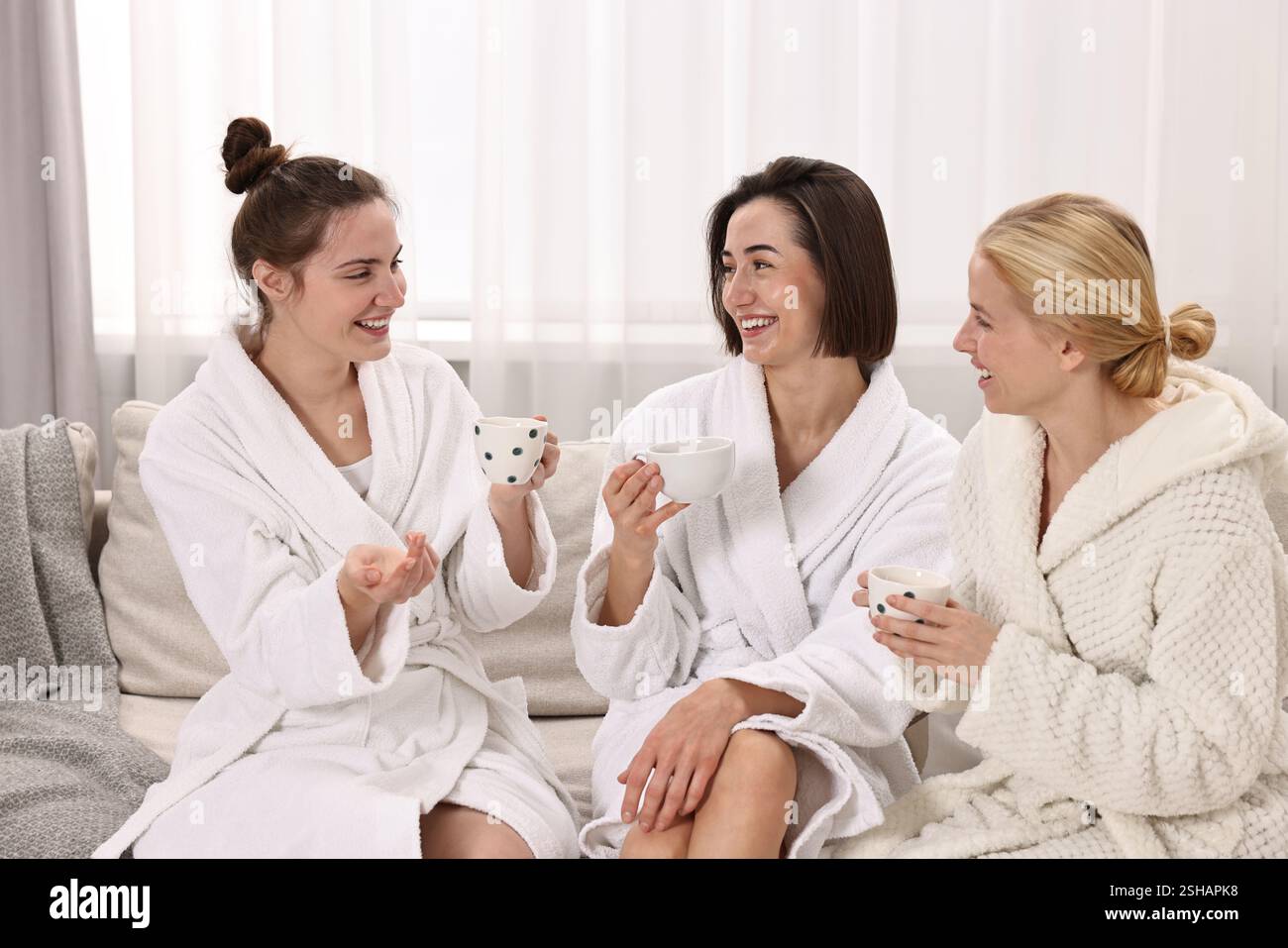 Beautiful women having tea on sofa in spa Stock Photo - Alamy