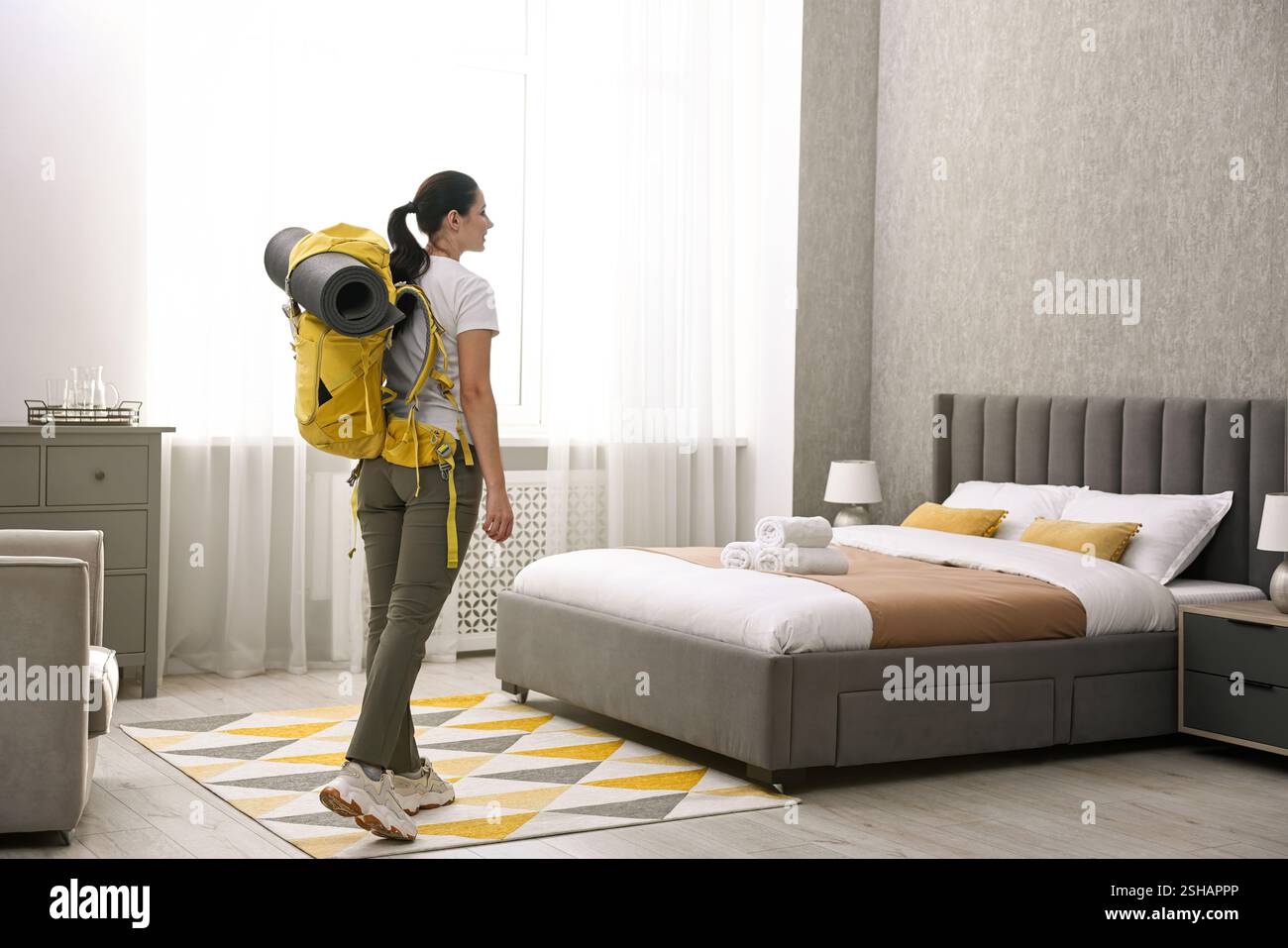 Traveller with backpack near bed in hotel room Stock Photo - Alamy