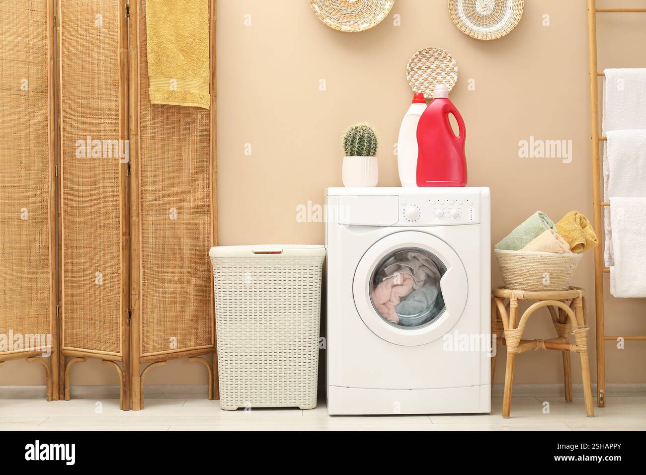Wicker laundry basket, washing machine and detergents in bathroom Stock ...