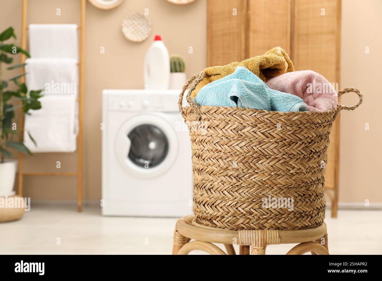 Wicker basket full of laundry on chair in bathroom Stock Photo - Alamy