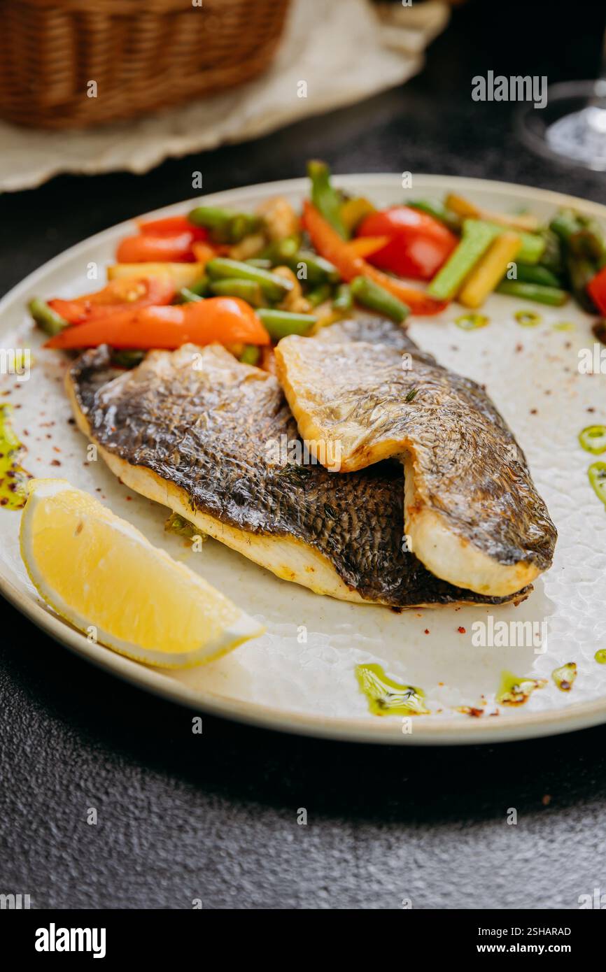 Grilled sea bream fillet with vegetables and lemon, plated with elegant ...