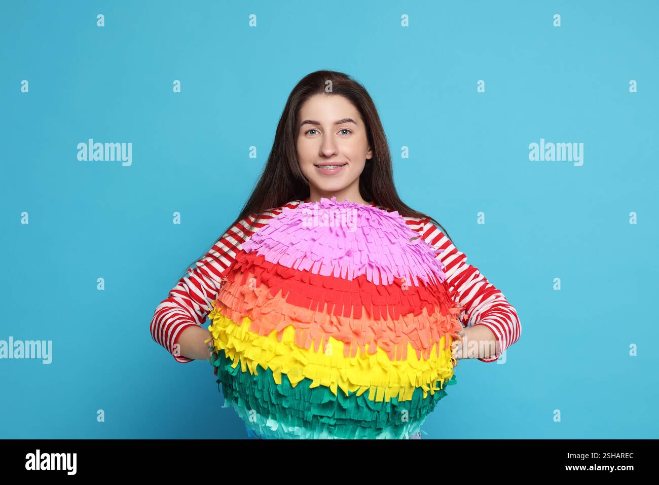 Happy woman with pinata on light blue background Stock Photo - Alamy