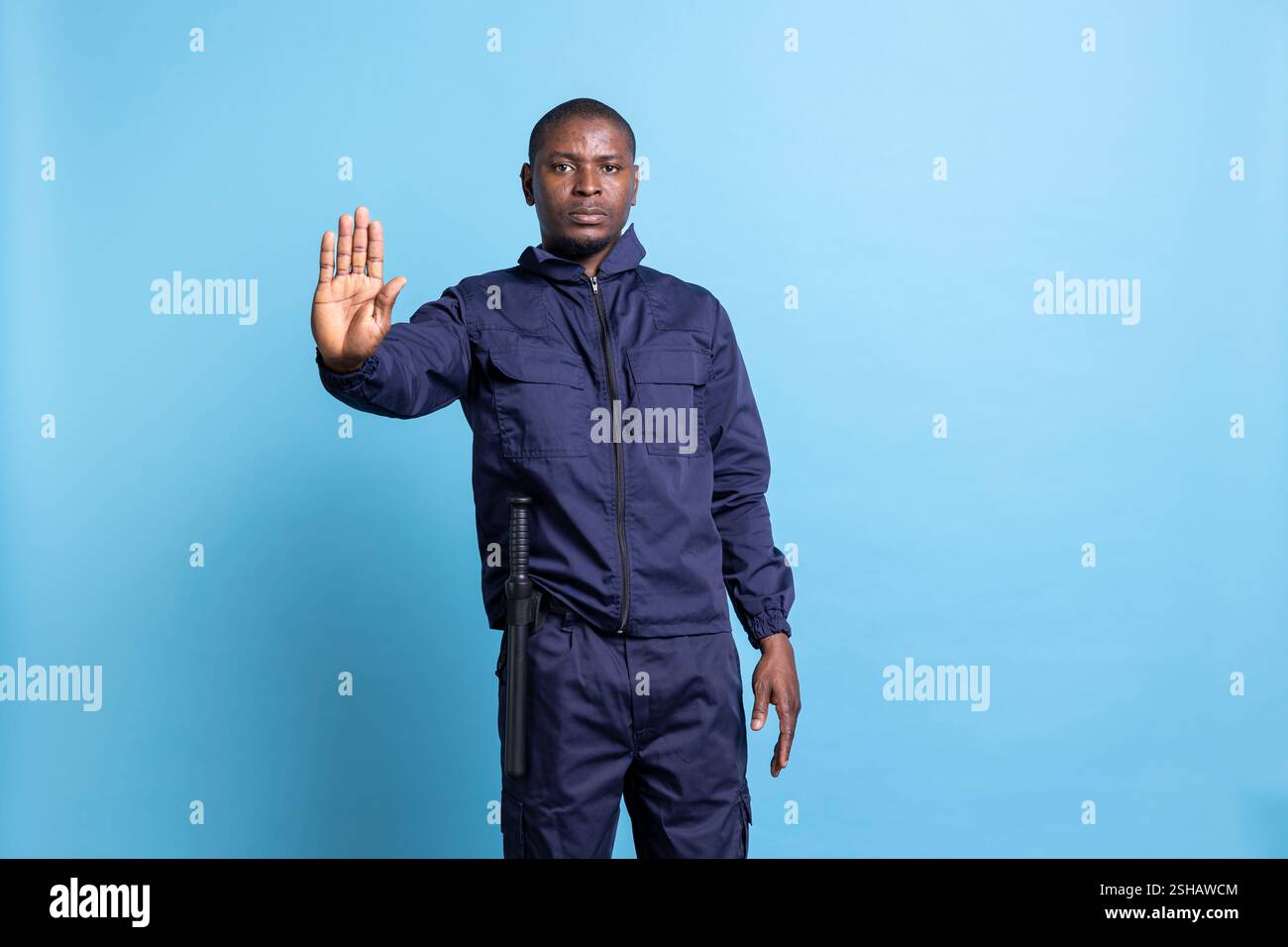 African american security warden does a stop sign with his palm raised ...