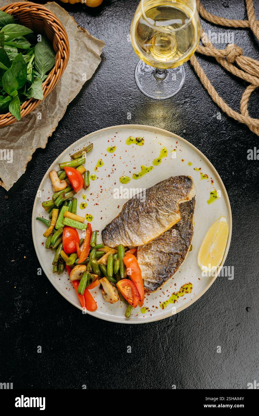 Grilled sea bream fillet with vegetables and lemon, plated with elegant ...