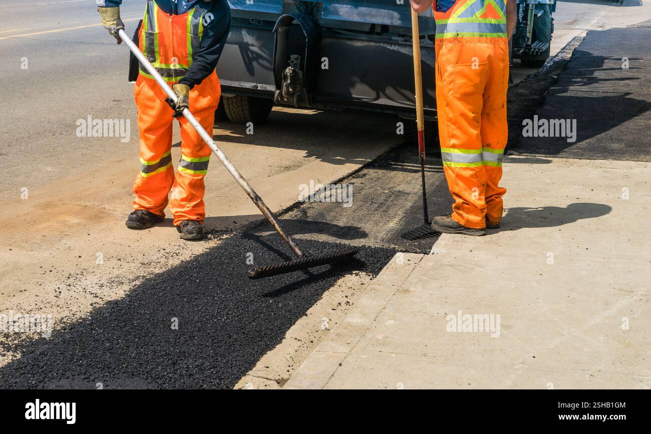 Workers leveling asphalt on construction site road repair Stock Photo ...