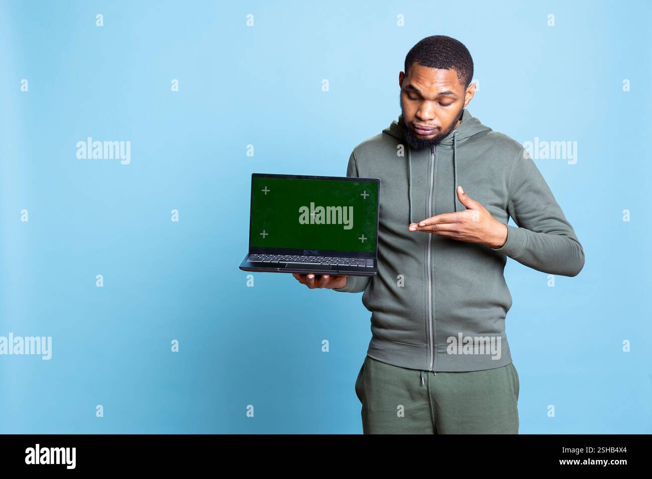 Smiling young adult presenting laptop with isolated mockup screen ...