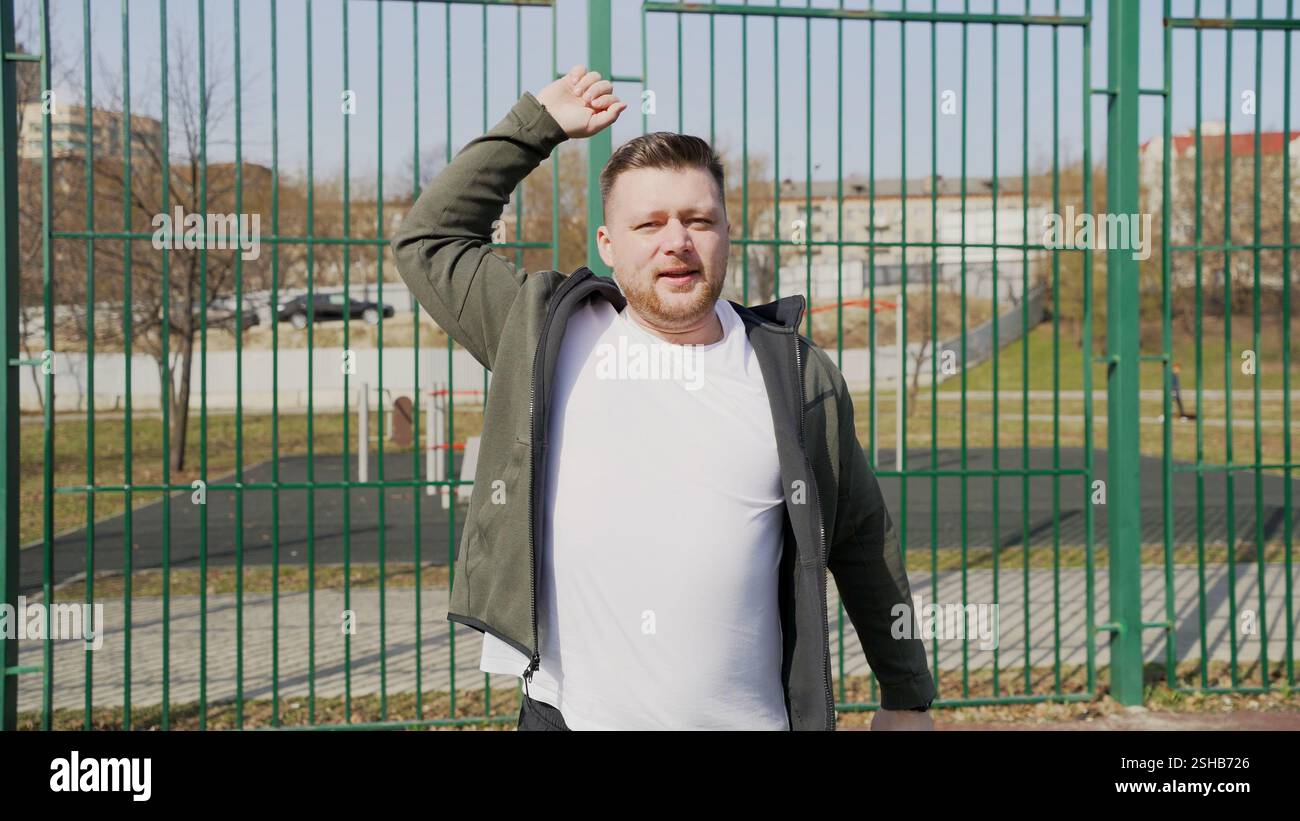Athletic male performing dynamic stretching routines near urban park ...
