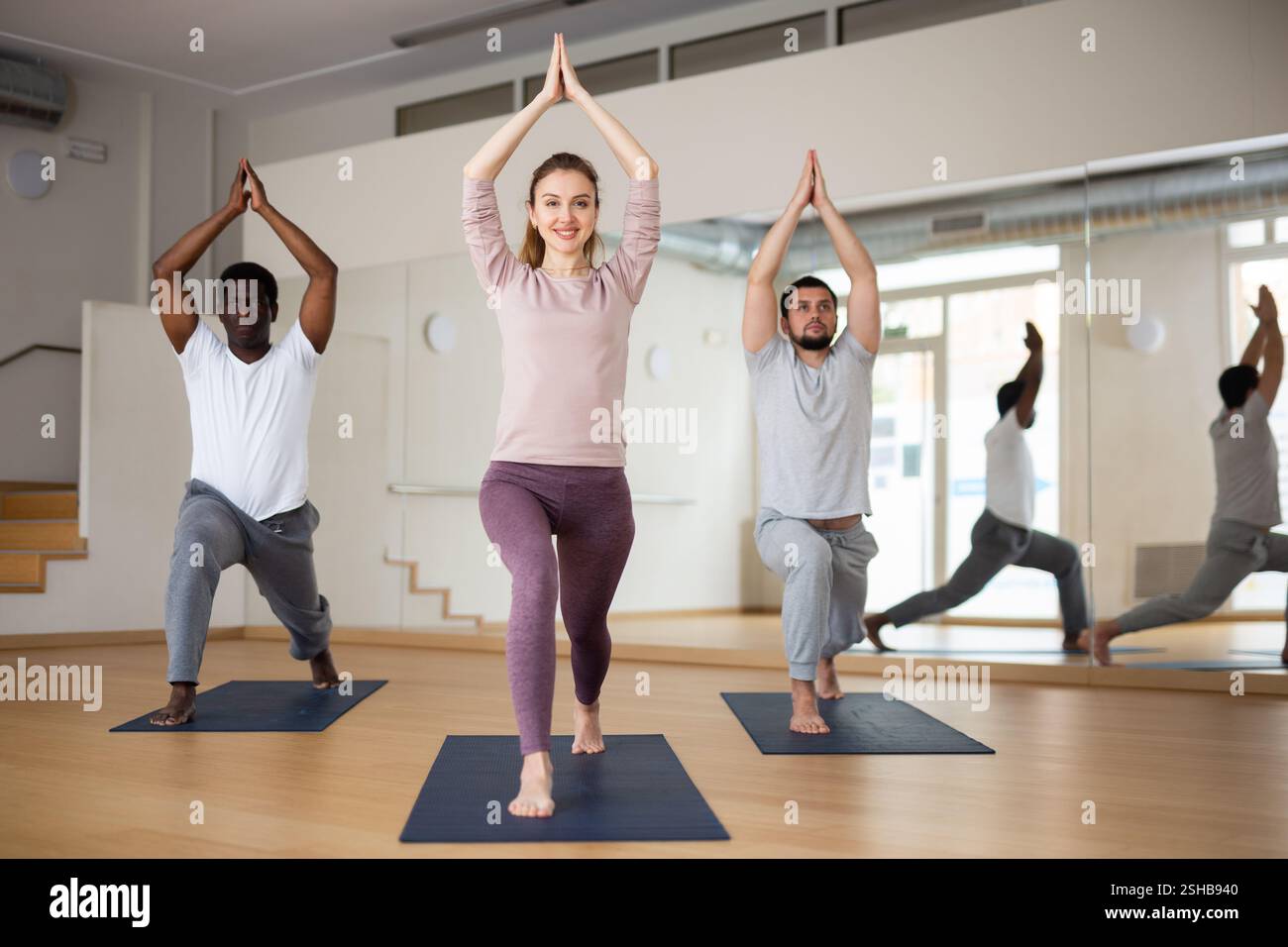 Woman doing Crescent High Lunge Pose with arms in prayer above head ...