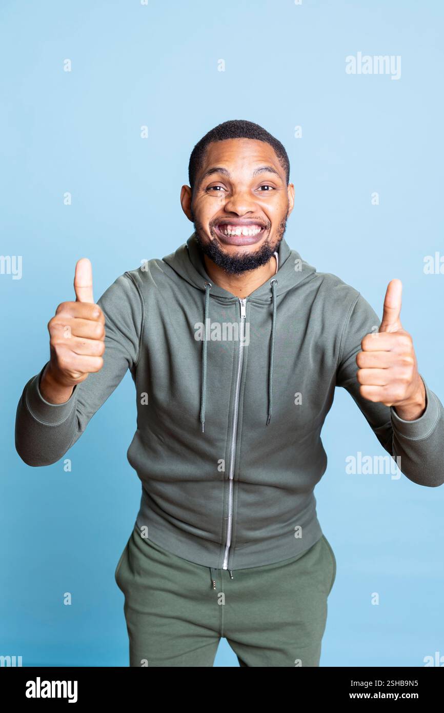 African american cheerful guy showing thumbs up sign against blue ...
