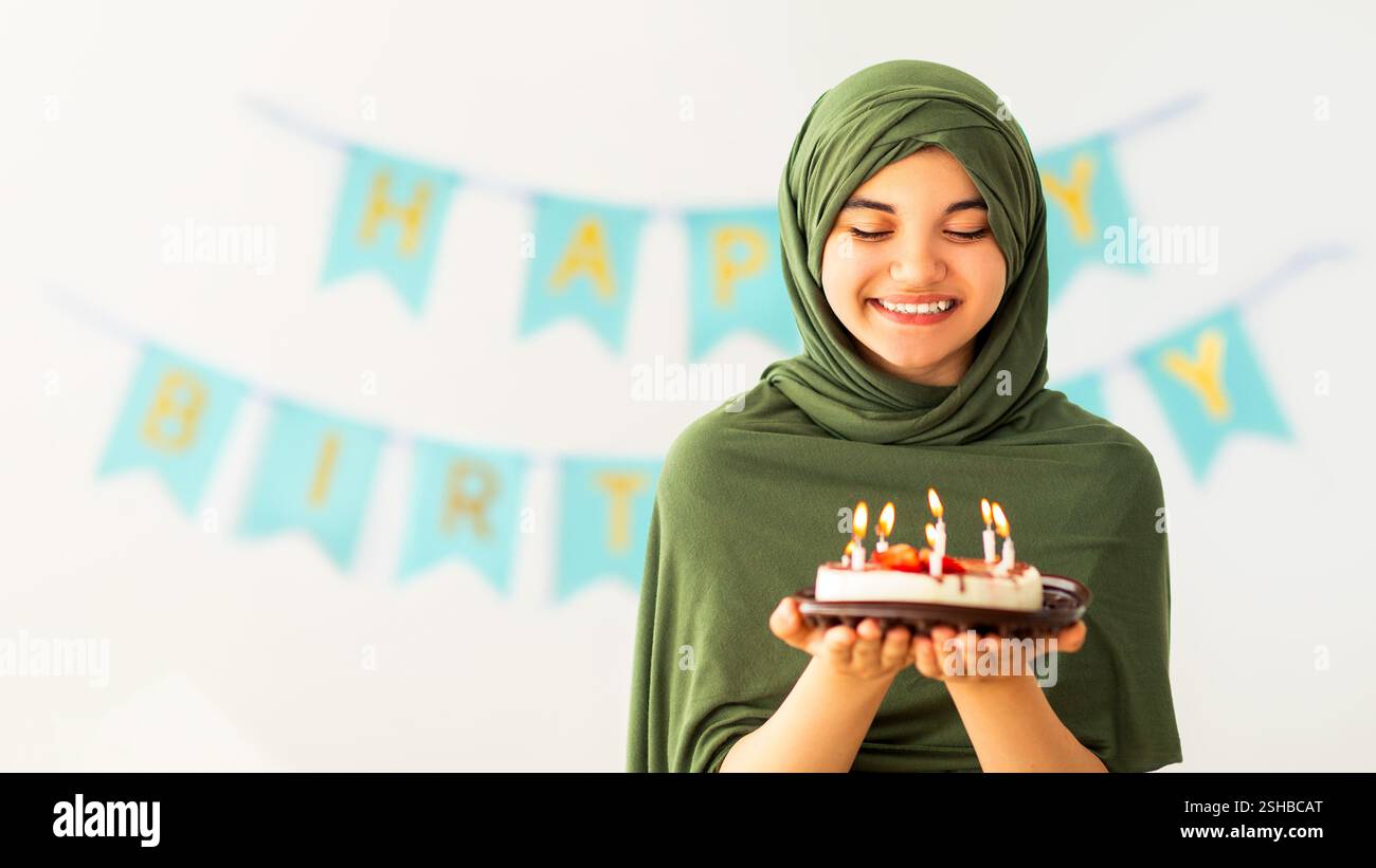 Muslim teen girl in hijab holding birthday cake with burning candles ...