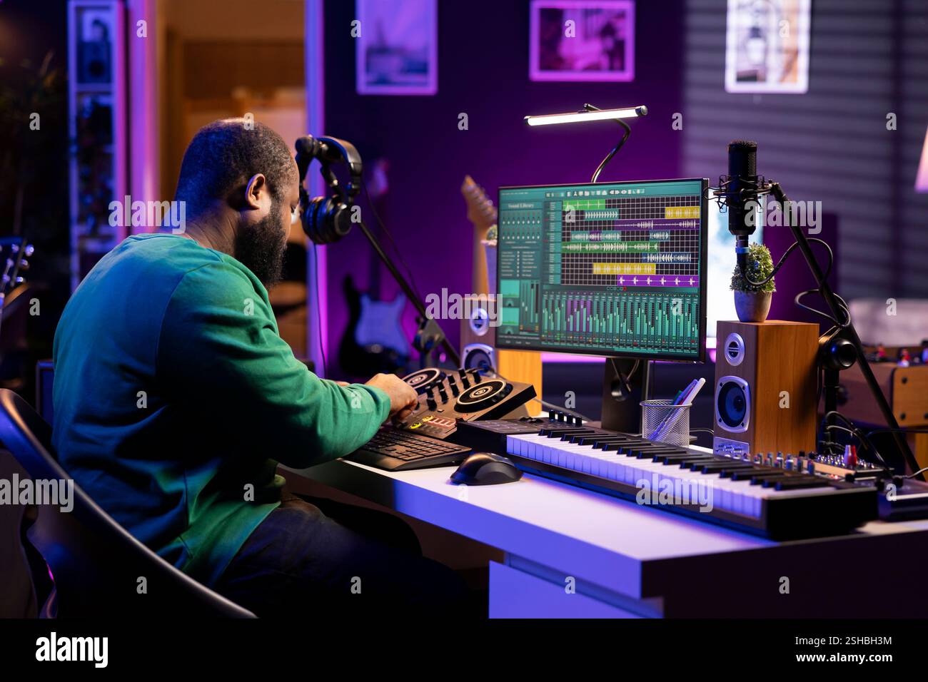 Skilled male composer producing new songs on his mixing console ...