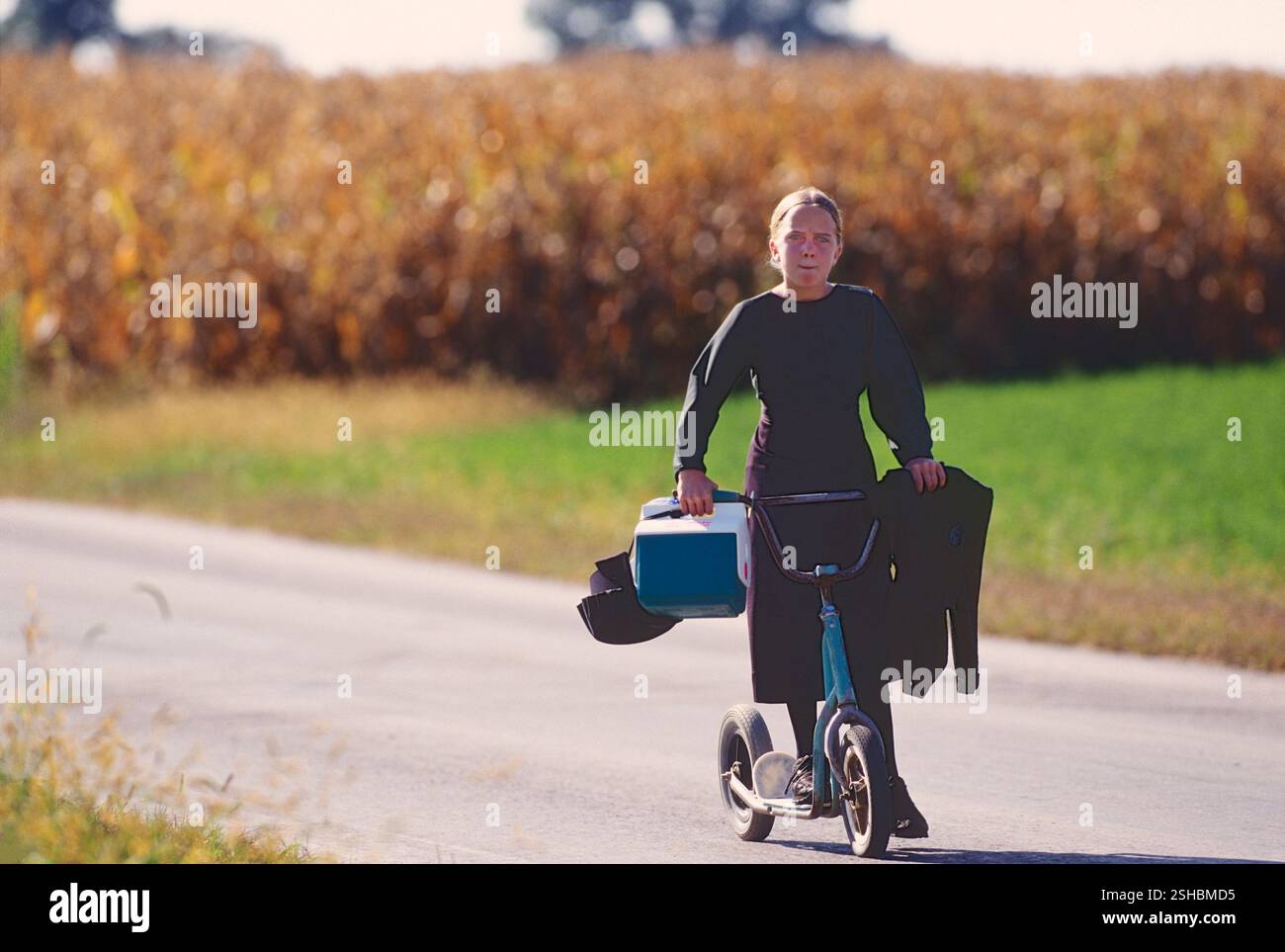 Amish children in traditional plain clothing ride scooters & biles to ...