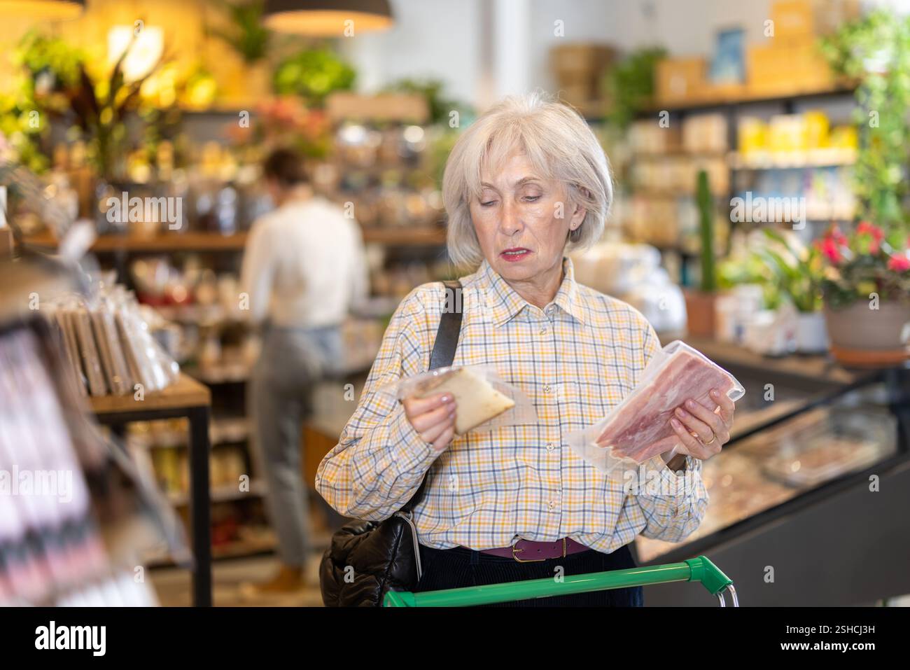 Mature woman choosing cheese and bacon Stock Photo - Alamy