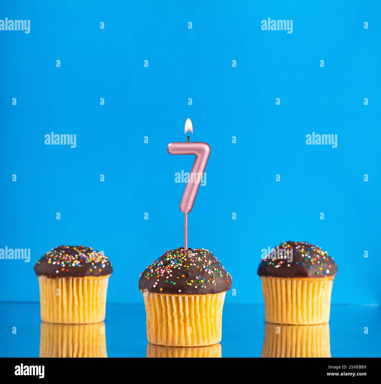 Three birthday cupcakes with number 7 candle - Blue background Stock ...