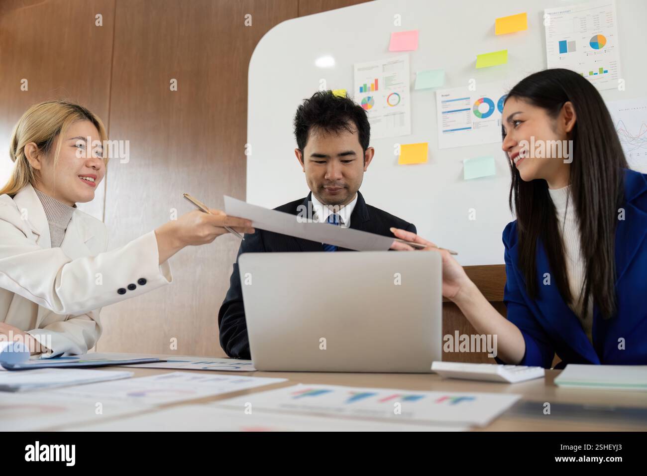Team members exchanging documents in a meeting, highlighting ...