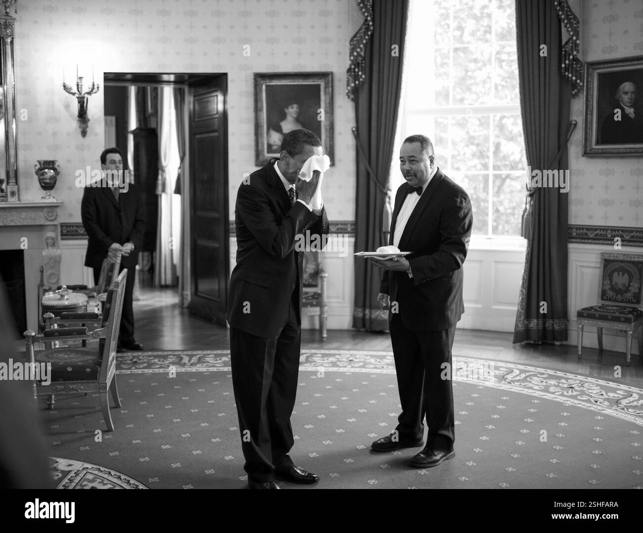 President Barack Obama wipes his face with a cloth handed to him by White House Butler Von ...