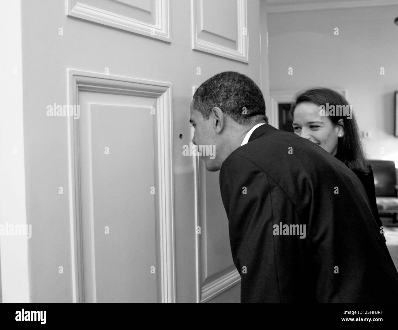 President Barack Obama looks through the Oval Office door peephole as ...