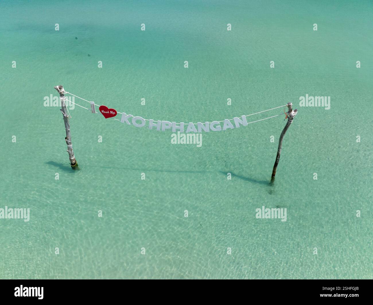 Koh Phangan sign suspended between wooden poles above tranquil ...