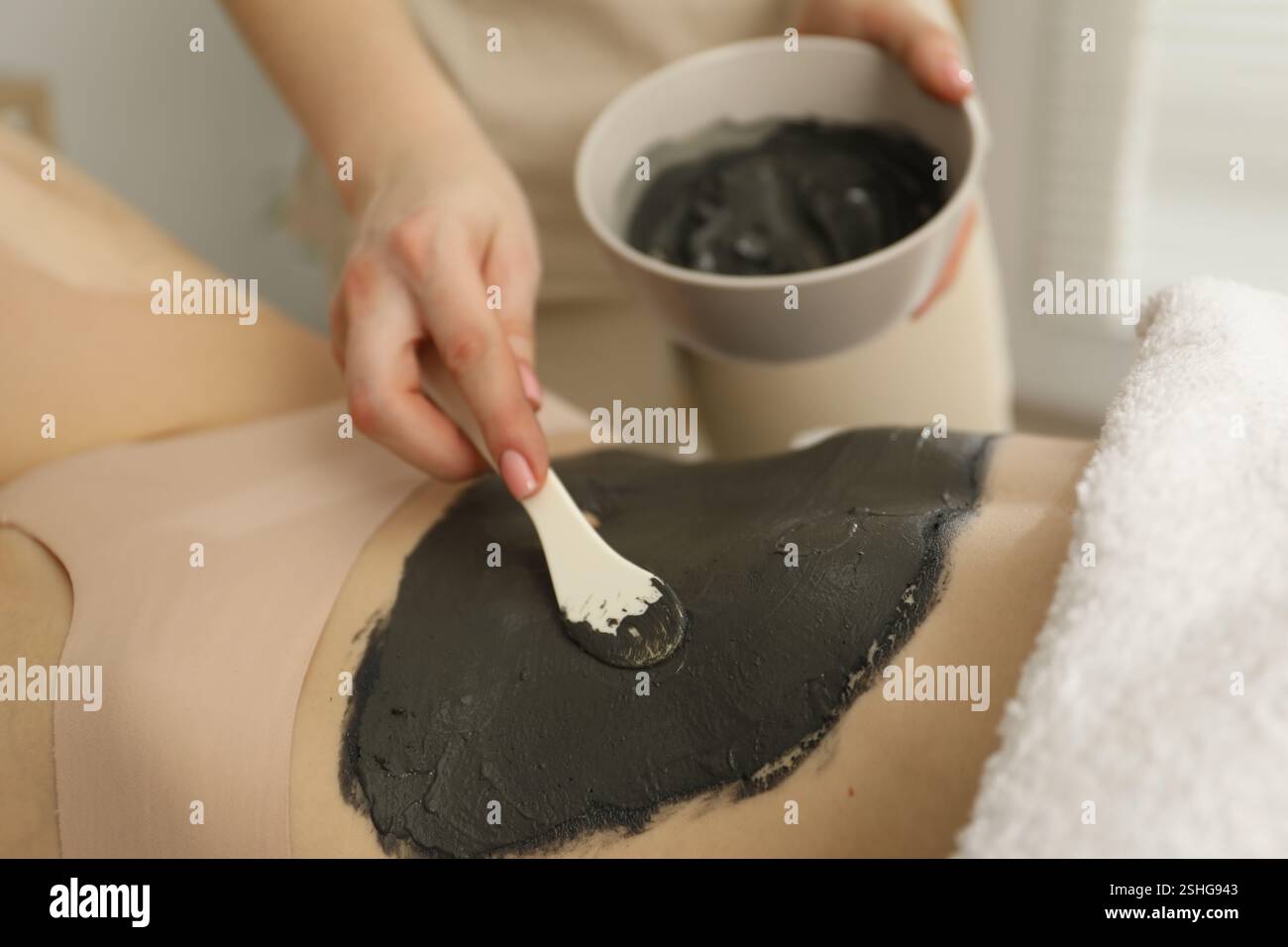 Esthetician applying cosmetic product for body wraps treatment onto ...