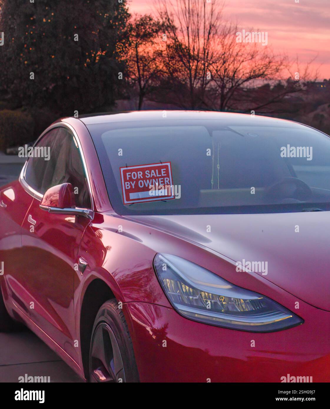 A red Tesla Model 3 with a For Sale sign on it at sunset. Tesla owners ...
