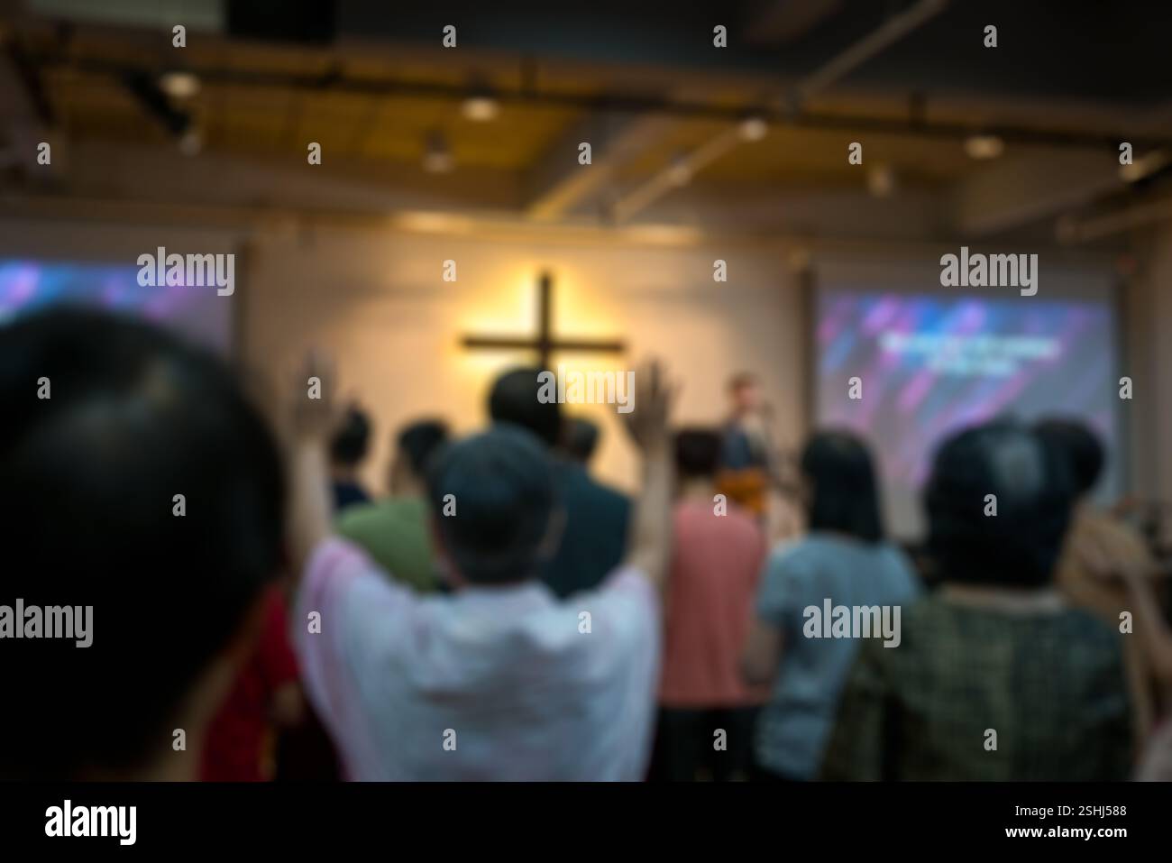 Back view of Christians worship with raised hands in church. Defocused ...