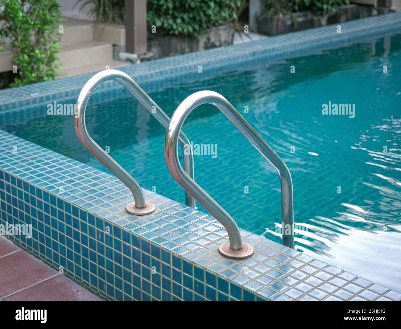 Swimming pool with stainless steel pool ladder Stock Photo - Alamy